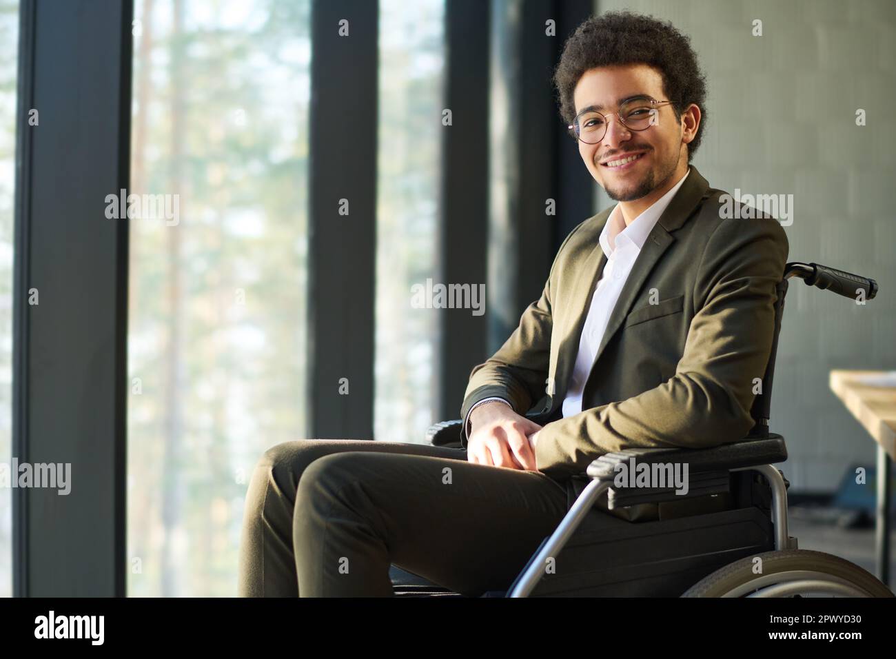 Happy young multi-ethnic businessman with disability sitting in ...