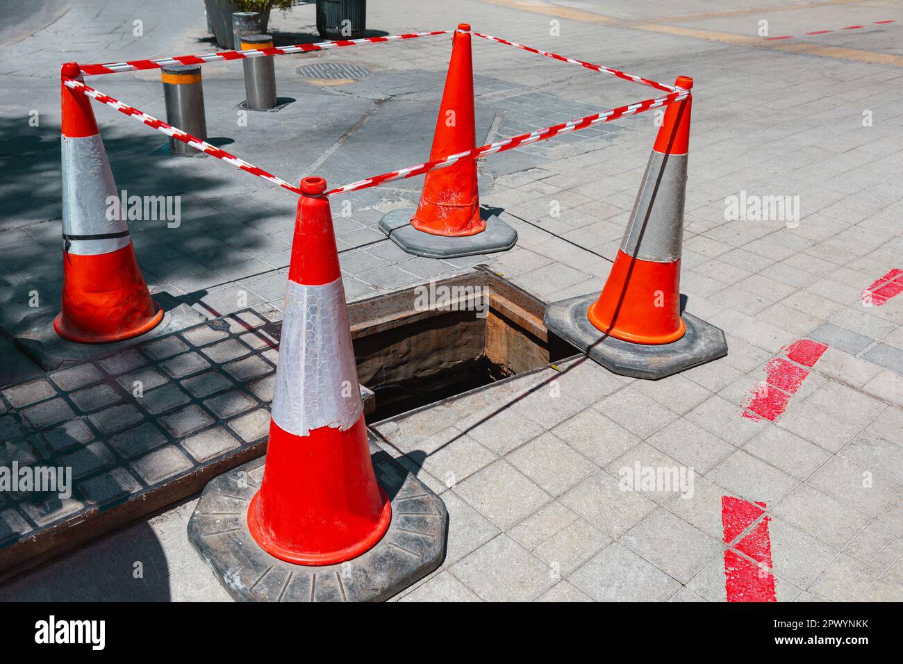 Street sinkhole repair . Red repair cones fencing the street Stock ...
