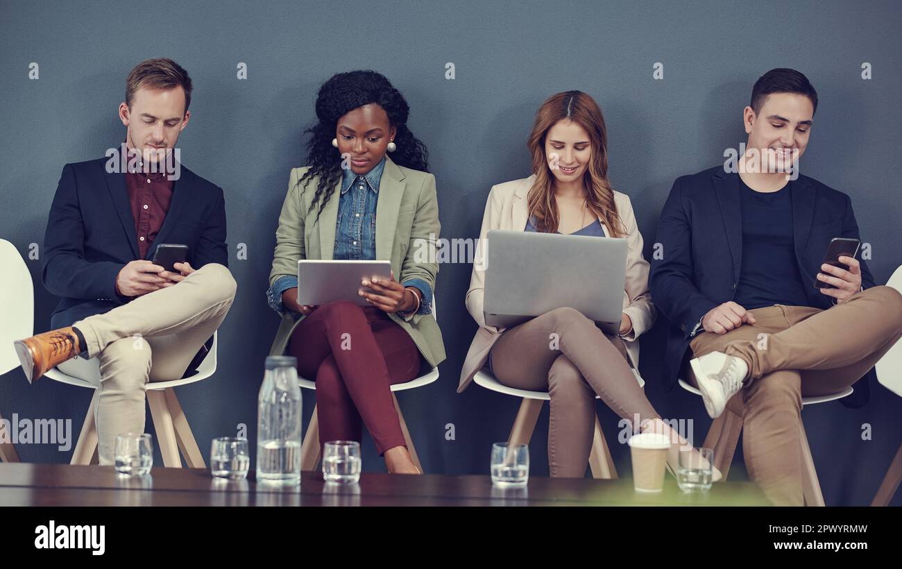Working while we waiting. a group of businesspeople using different ...