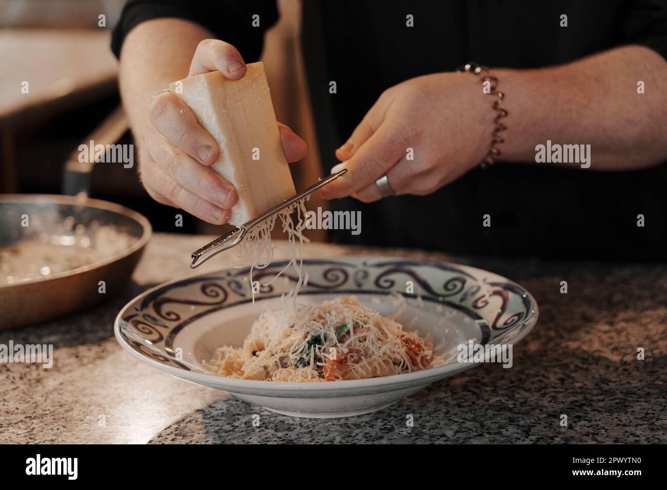 Crop male cook grating Parmesan cheese into dish Stock Photo - Alamy