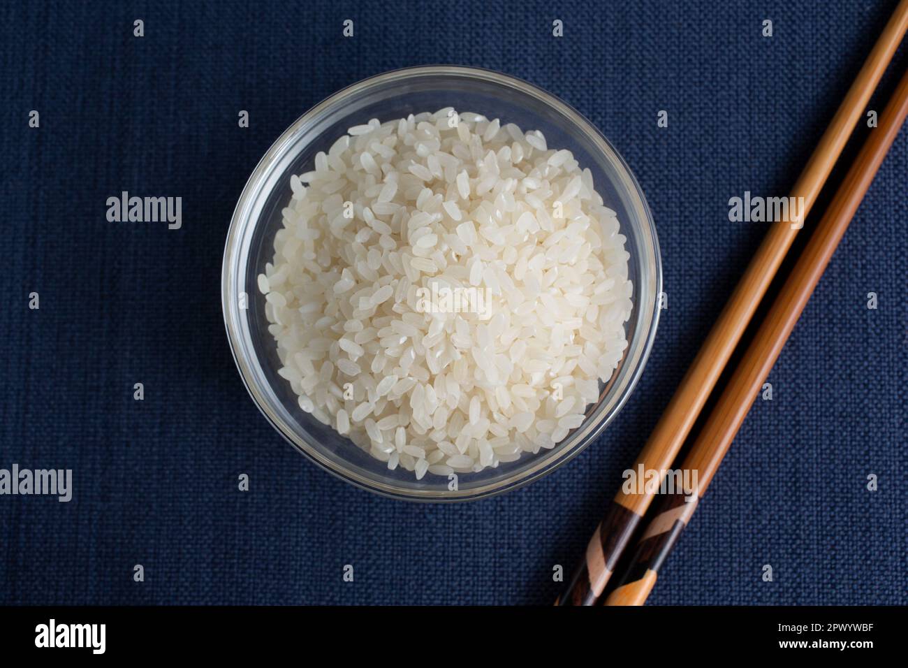 A top down view of a glass bowl of short grain rice, with chopsticks on ...