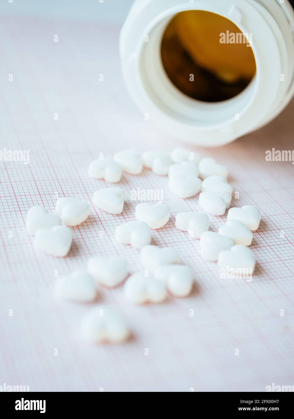 White medical cardiological pills in the form of heart and a bottle of ...