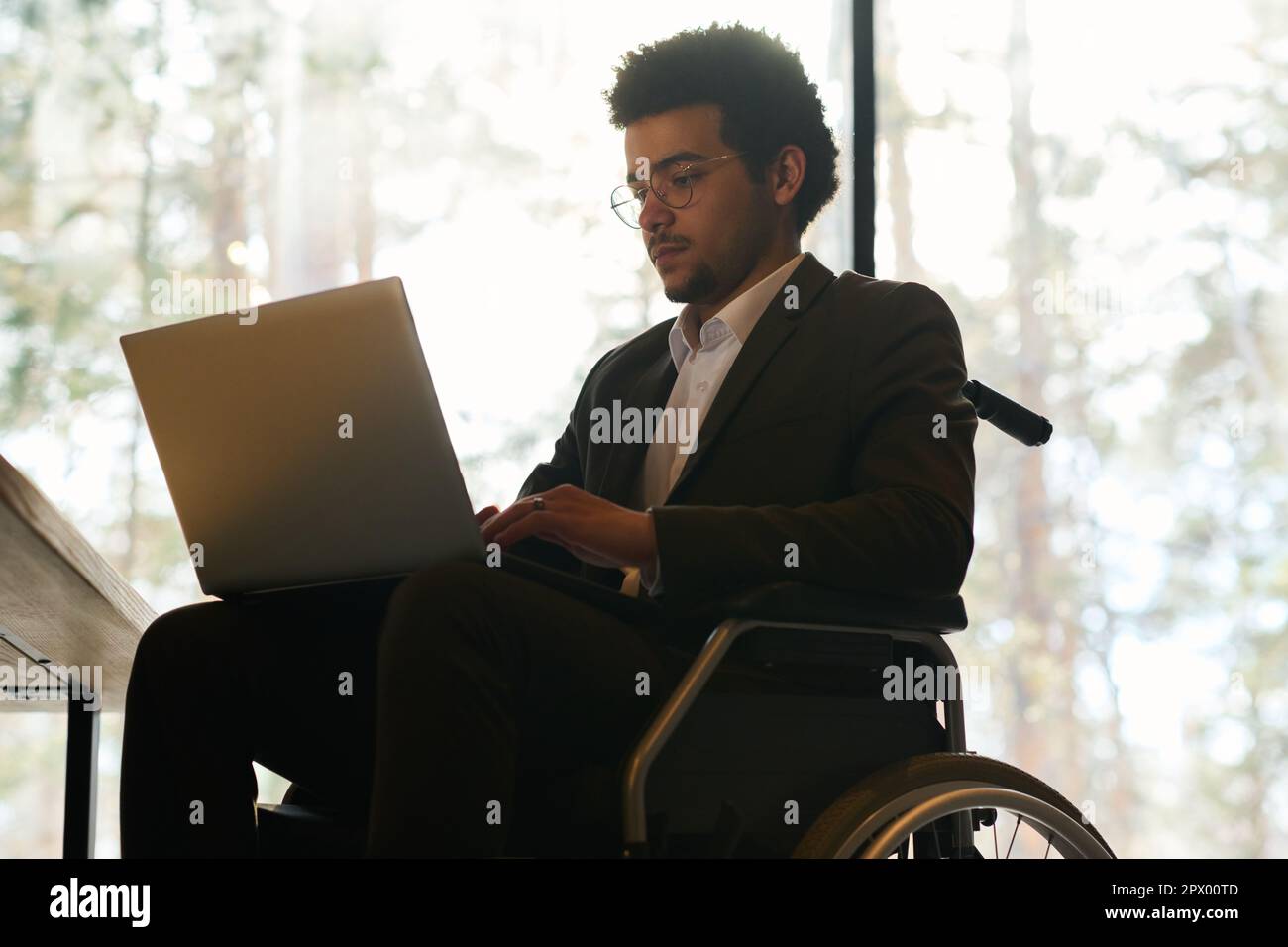 Young multi-ethnic businessman with disability using laptop while ...