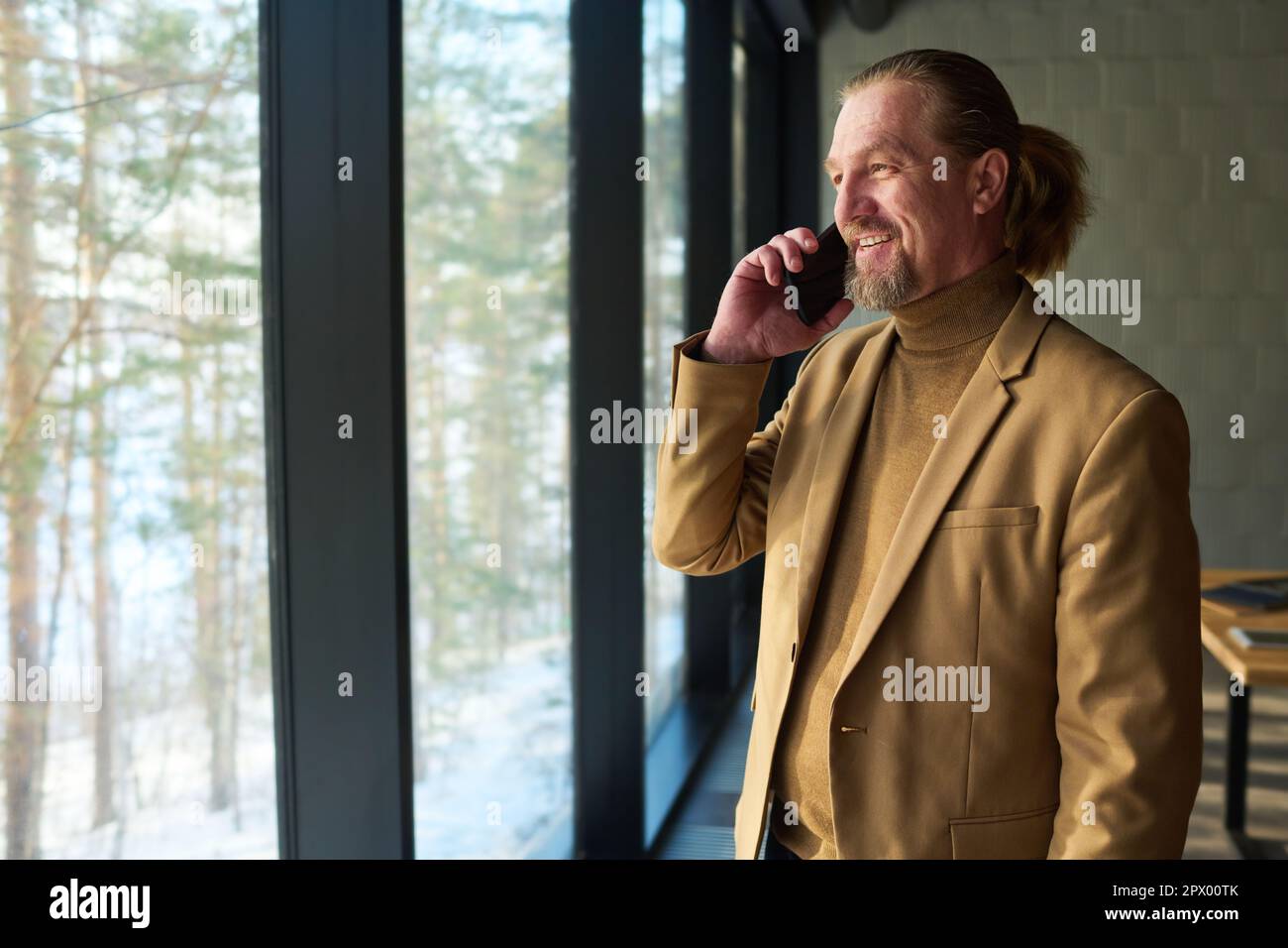 Smiling chief executive officer in formalwear looking through large ...