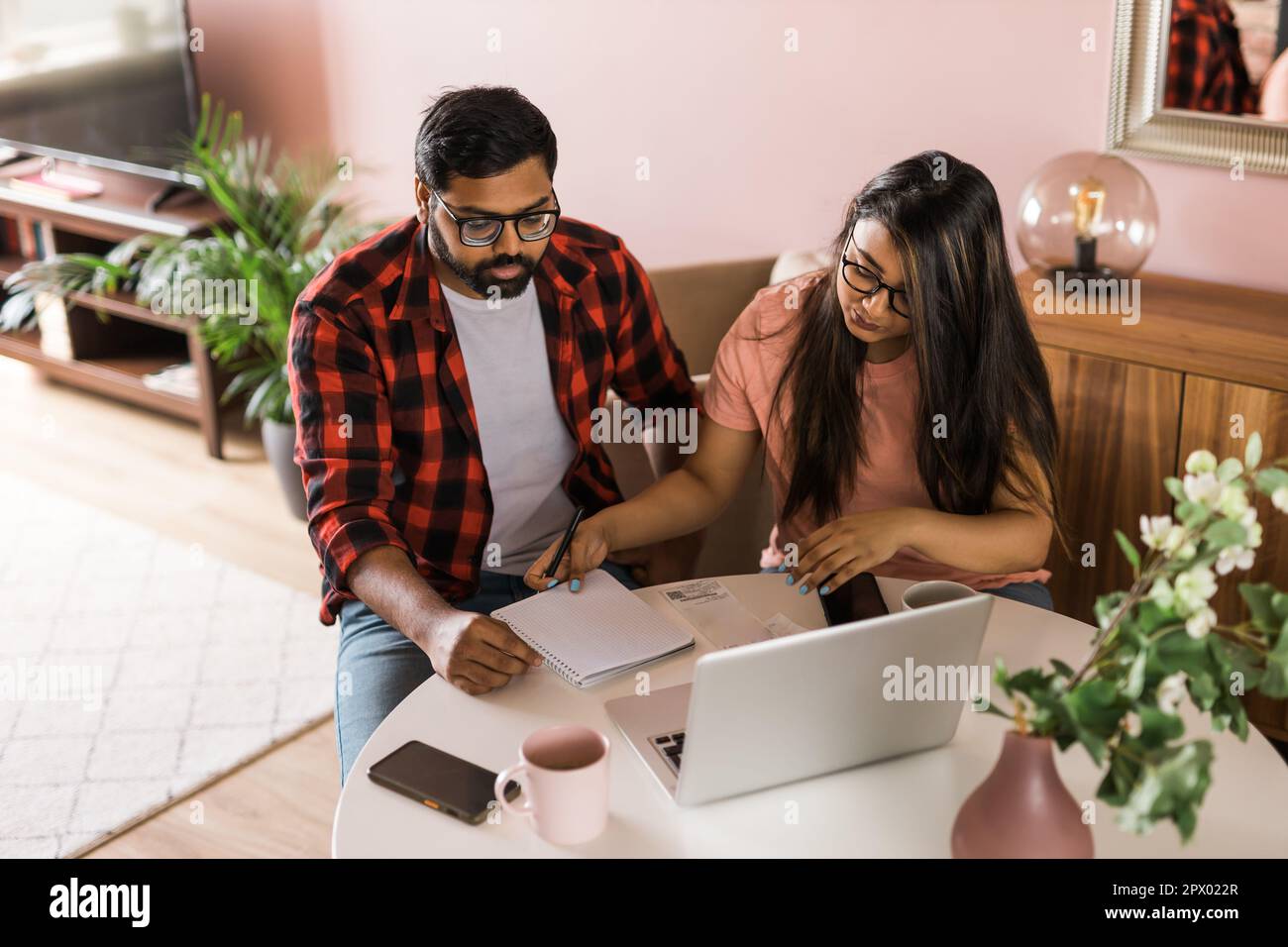 Young millennial indian husband and wife doing domestic paperwork ...
