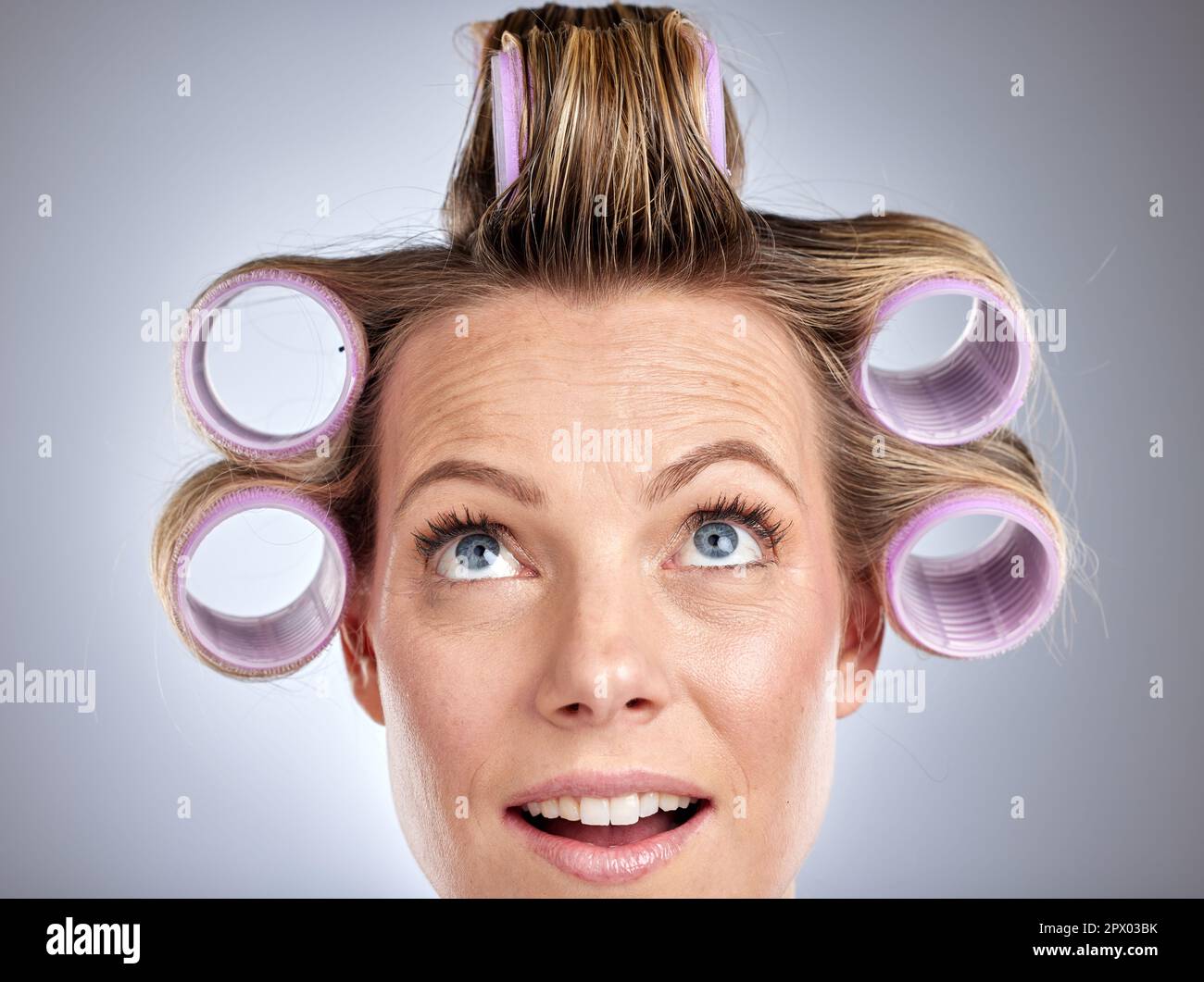 Hair, rollers and beauty with a model woman in studio on a gray ...