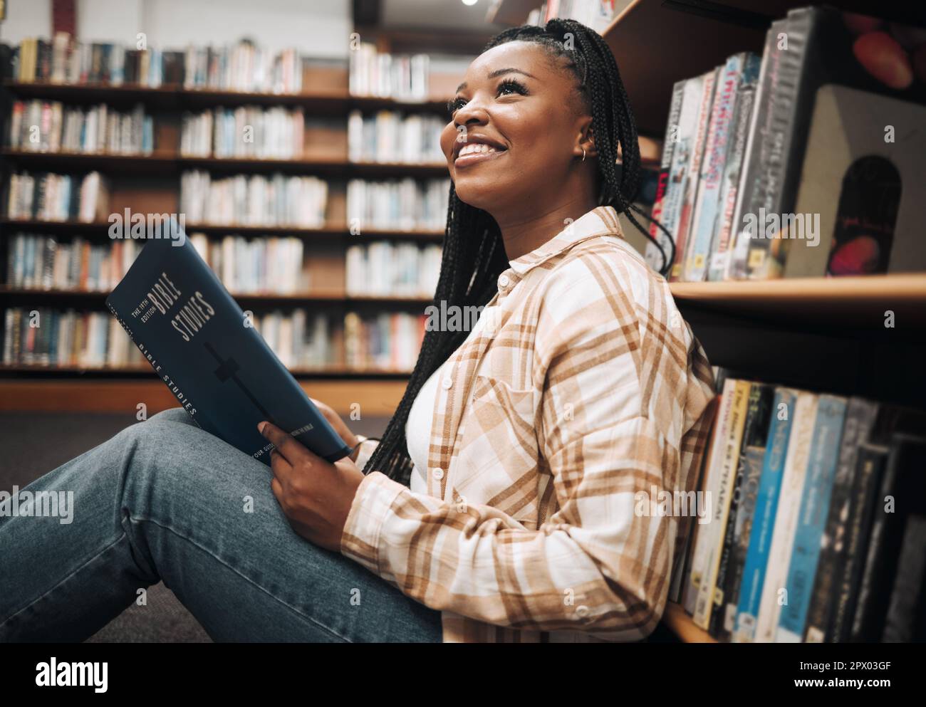 Black woman student, reading or library floor for religion, study or bible in research, focus or ...