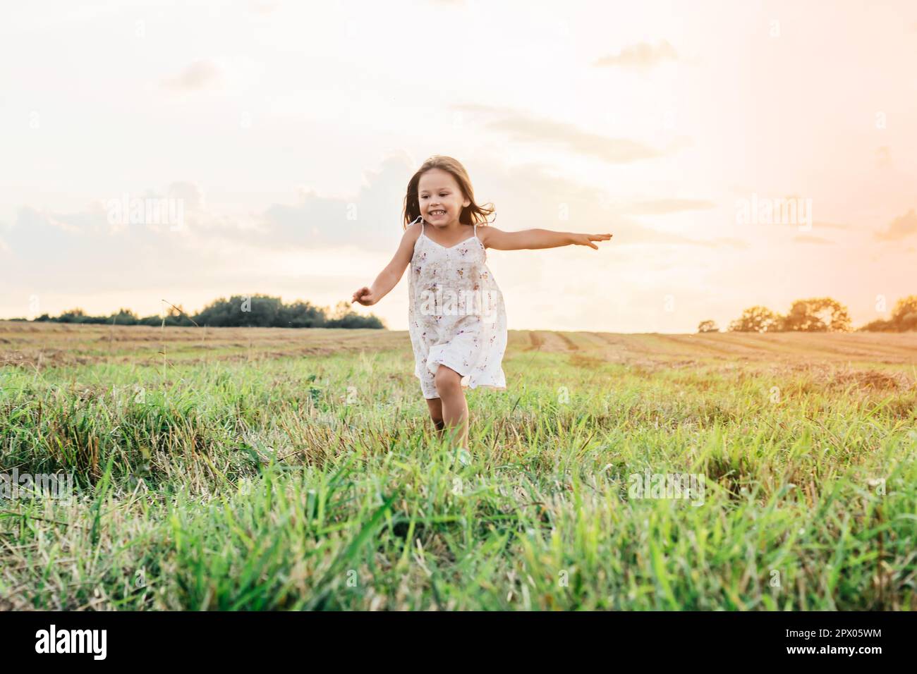 Happy little girl joyfully running across field. Carefree child on ...