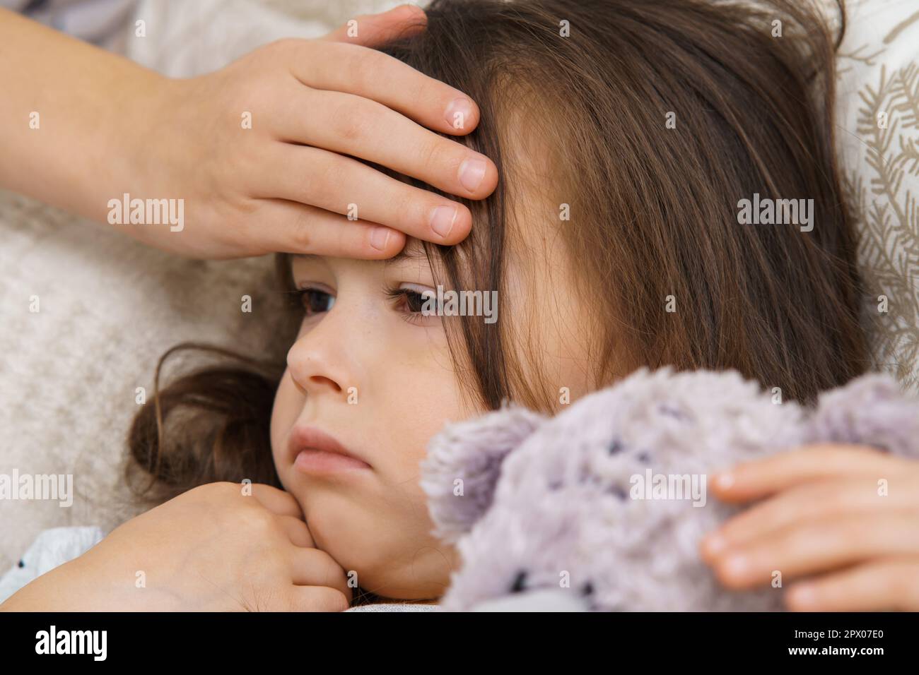 Hand of child touch hot forehead of sick little girl. Portrait closeup ...