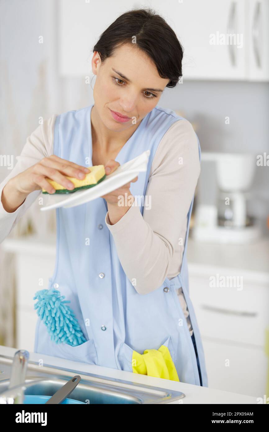 happy woman standing at kitchen sink washing up Stock Photo - Alamy