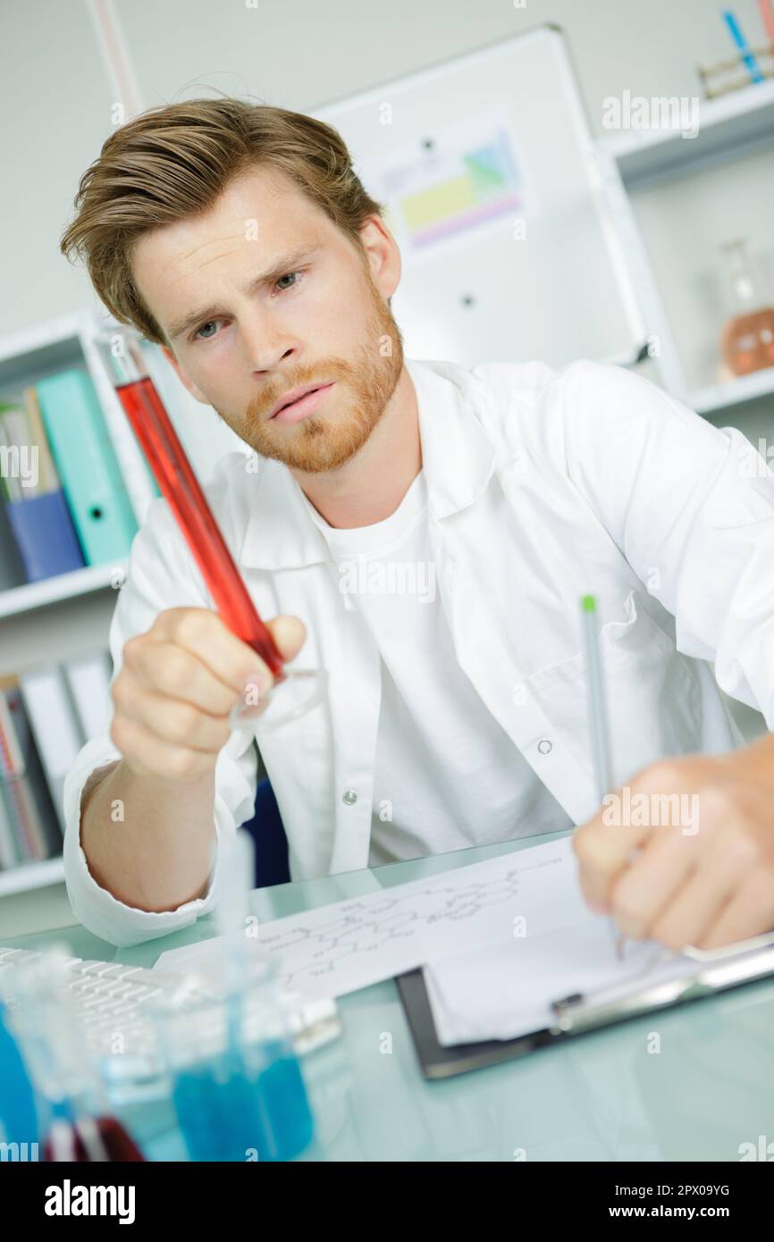 male scientist examining glass cylinder containing red liquid Stock ...