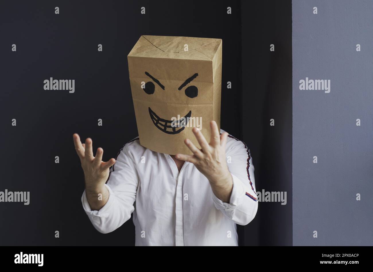A man in a white shirt with a paper bag with an angry emoticon on his ...