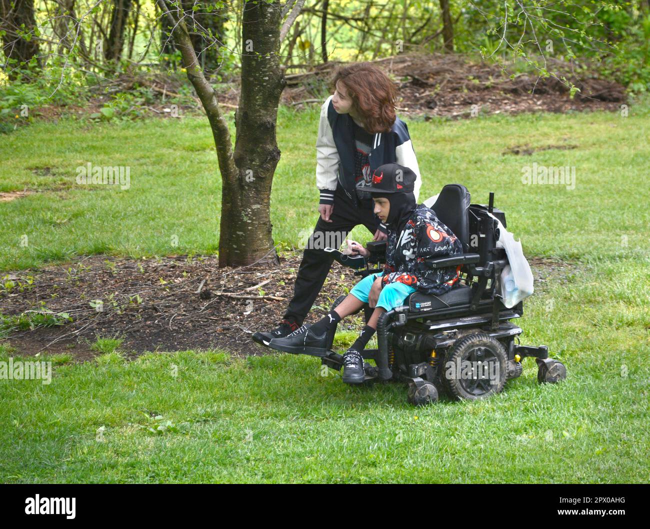 A disabled young man in a motorized wheelchair with his assistant in ...