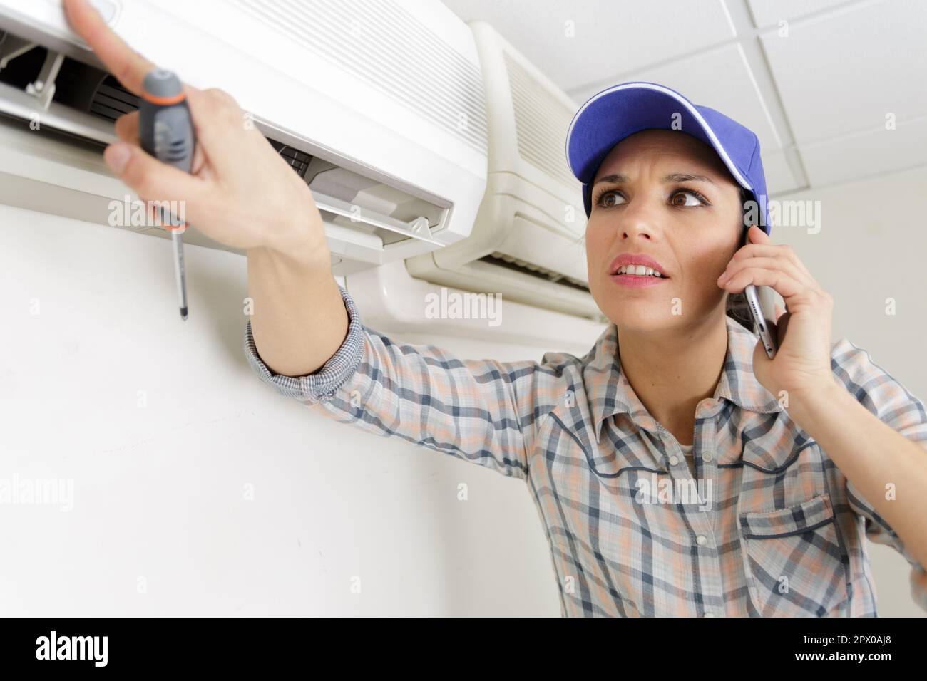 female engineer repairing air conditioning system calling for help ...