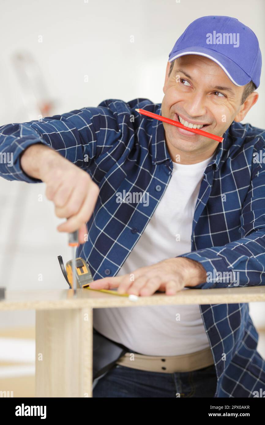 man assembling furniture holding pencil between his teeth Stock Photo ...