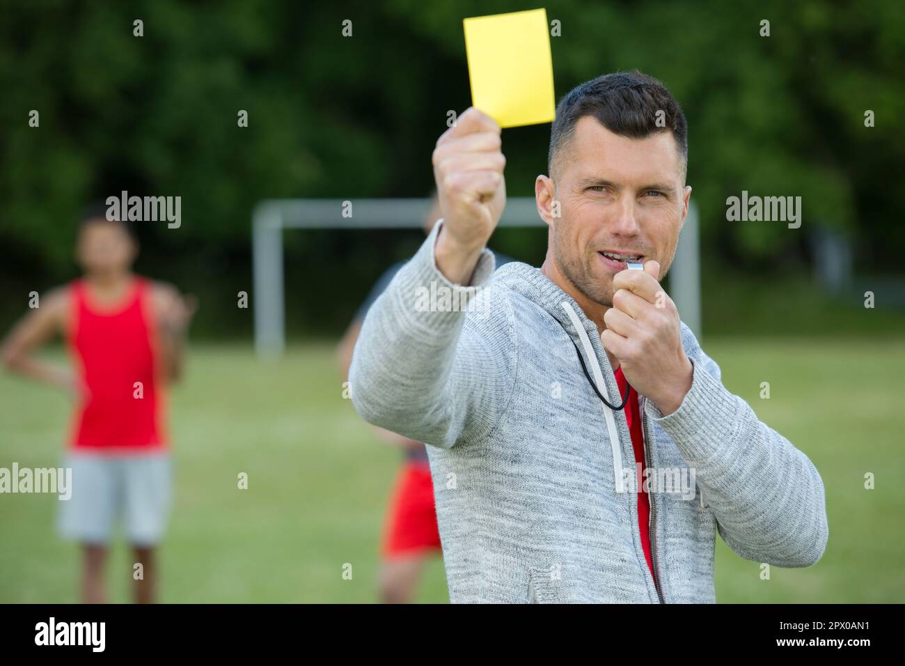 referee on football field showing yellow card Stock Photo - Alamy