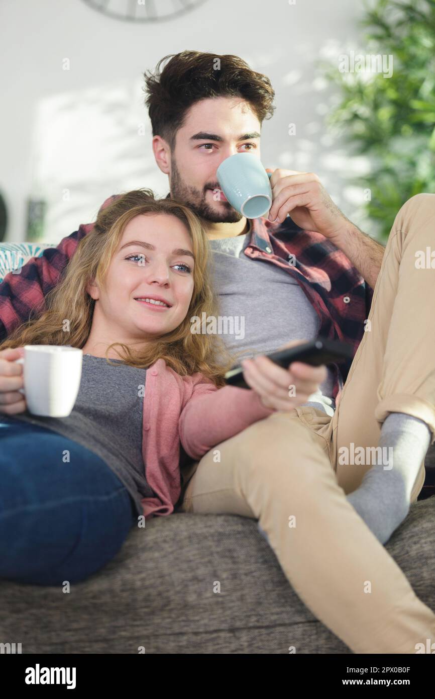 couple resting on the sofa holding remote control Stock Photo - Alamy