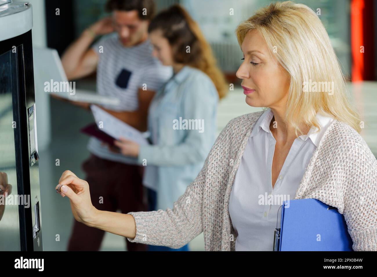 mature woman inserting coin into vending machine Stock Photo - Alamy