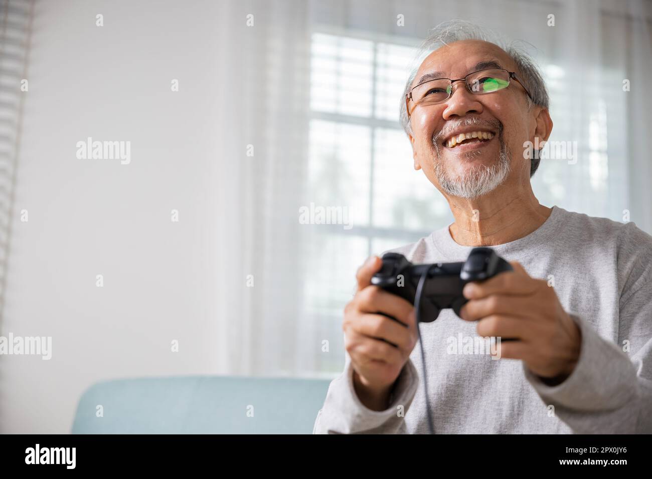 Asian senior old man enjoying holding joystick playing video game at ...