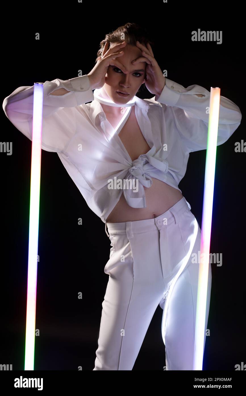 Confident young androgynous male model in white shirt and pants with ...