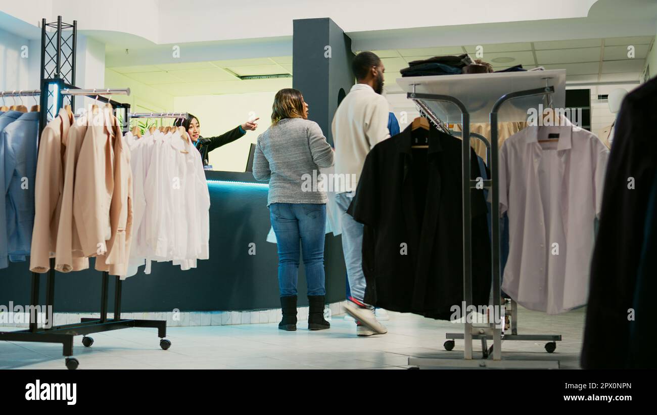 Happy customer going to fitting room to try on shirts, looking at ...