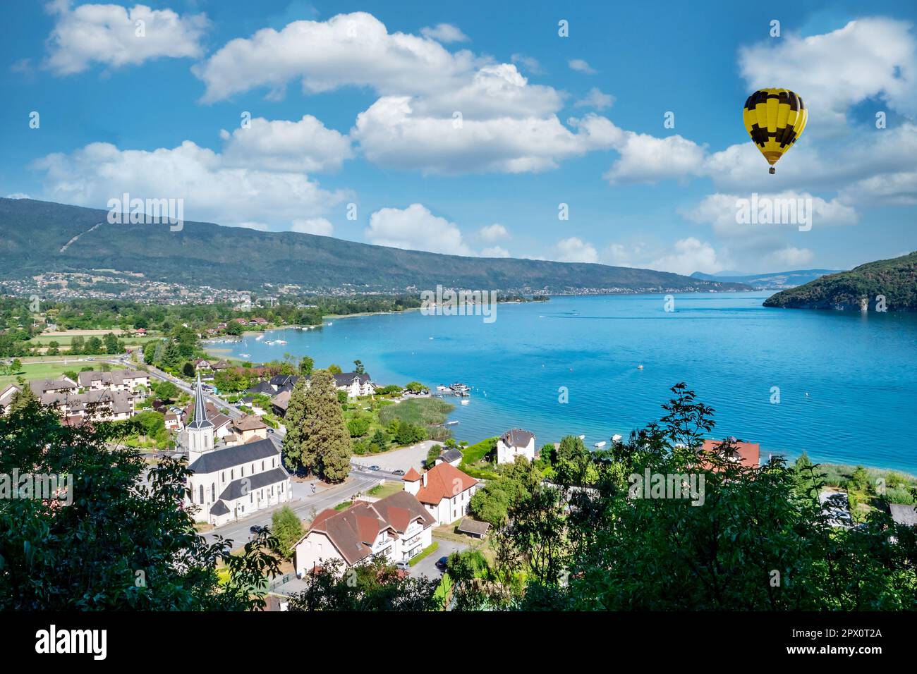 a yellow hot air balloon flying over Annecy lake in the morning, France ...