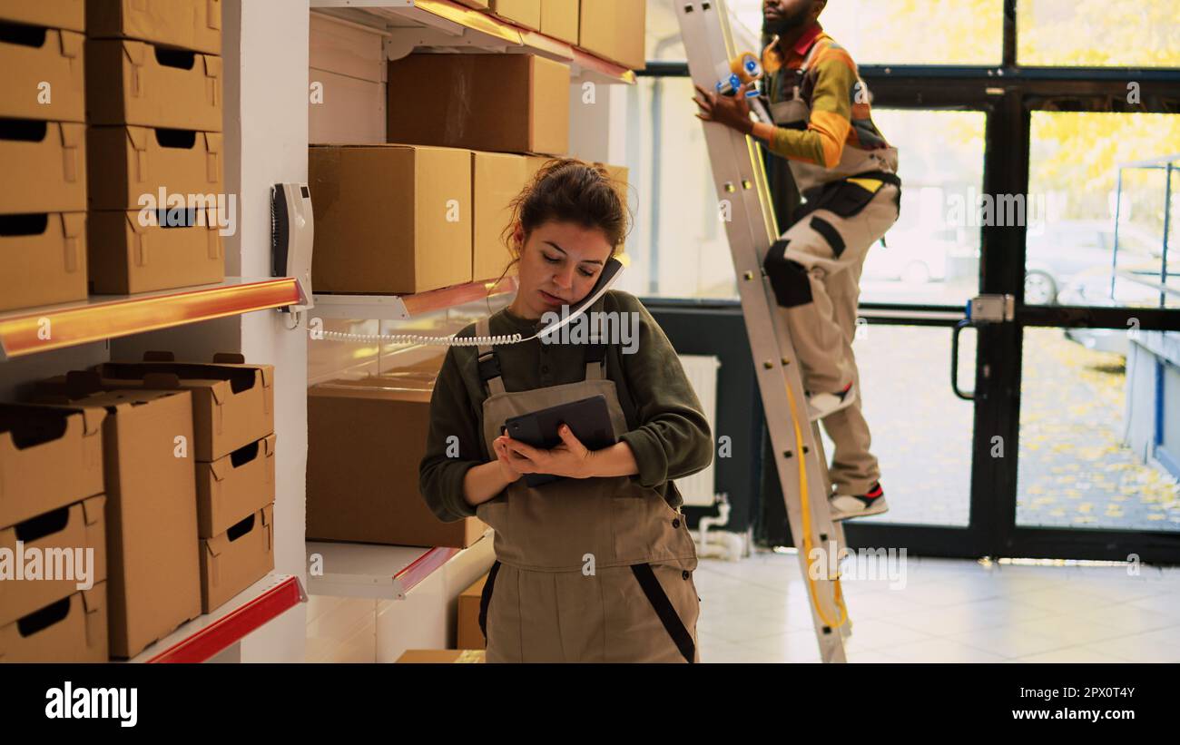 Depot manager talking on landline phone to inspect products logistics ...