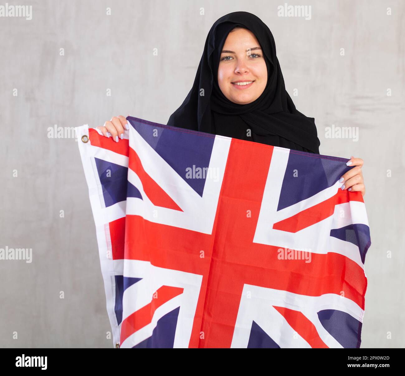 smiling Muslim woman in traditional black hijab holds flag of Great Britain Stock Photo - Alamy