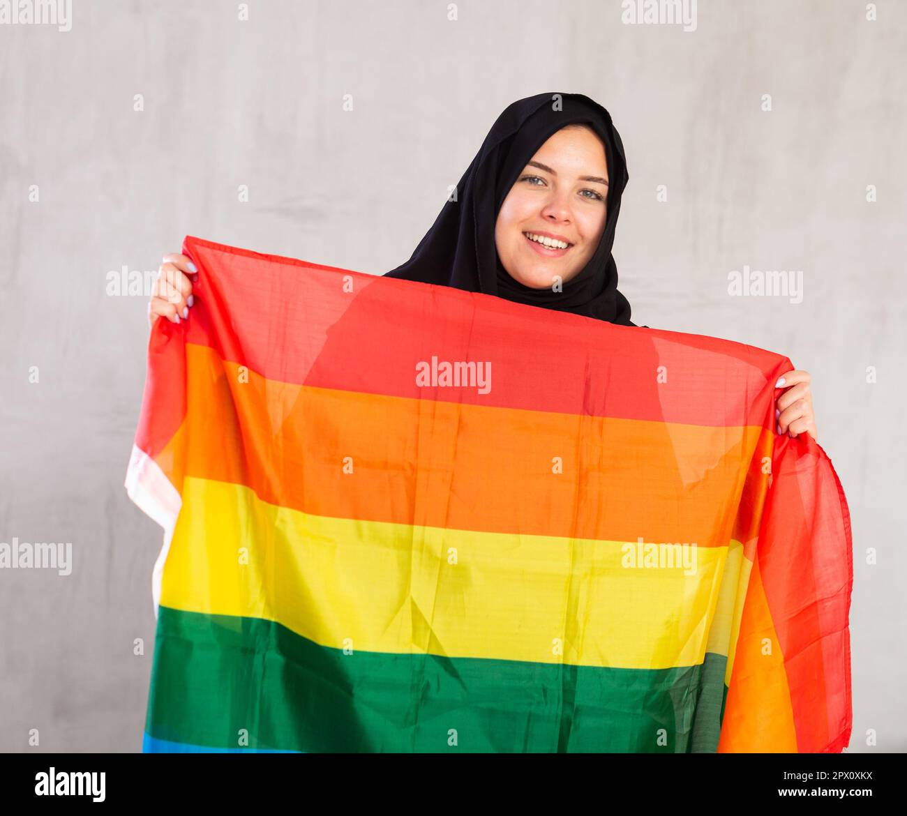 Happy young woman dressed in traditional islamic clothes with rainbow ...