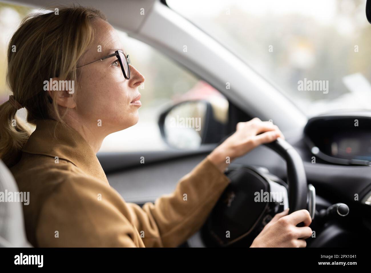 Business woman driving a car to work. Female driver steering car on the ...