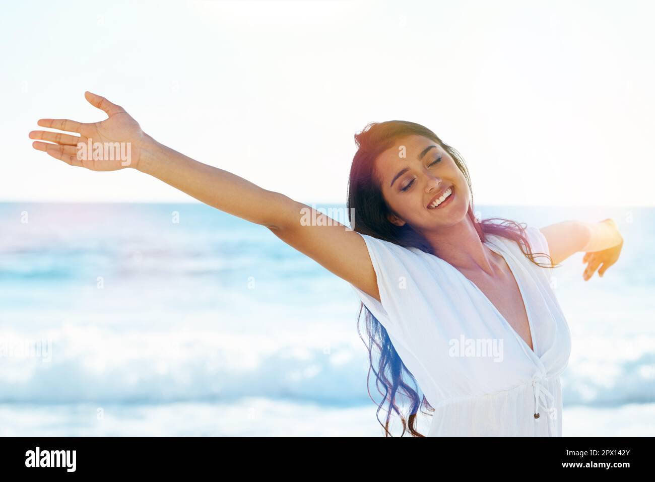 Embracing the freedom. Beautiful woman on the beach with her arms ...