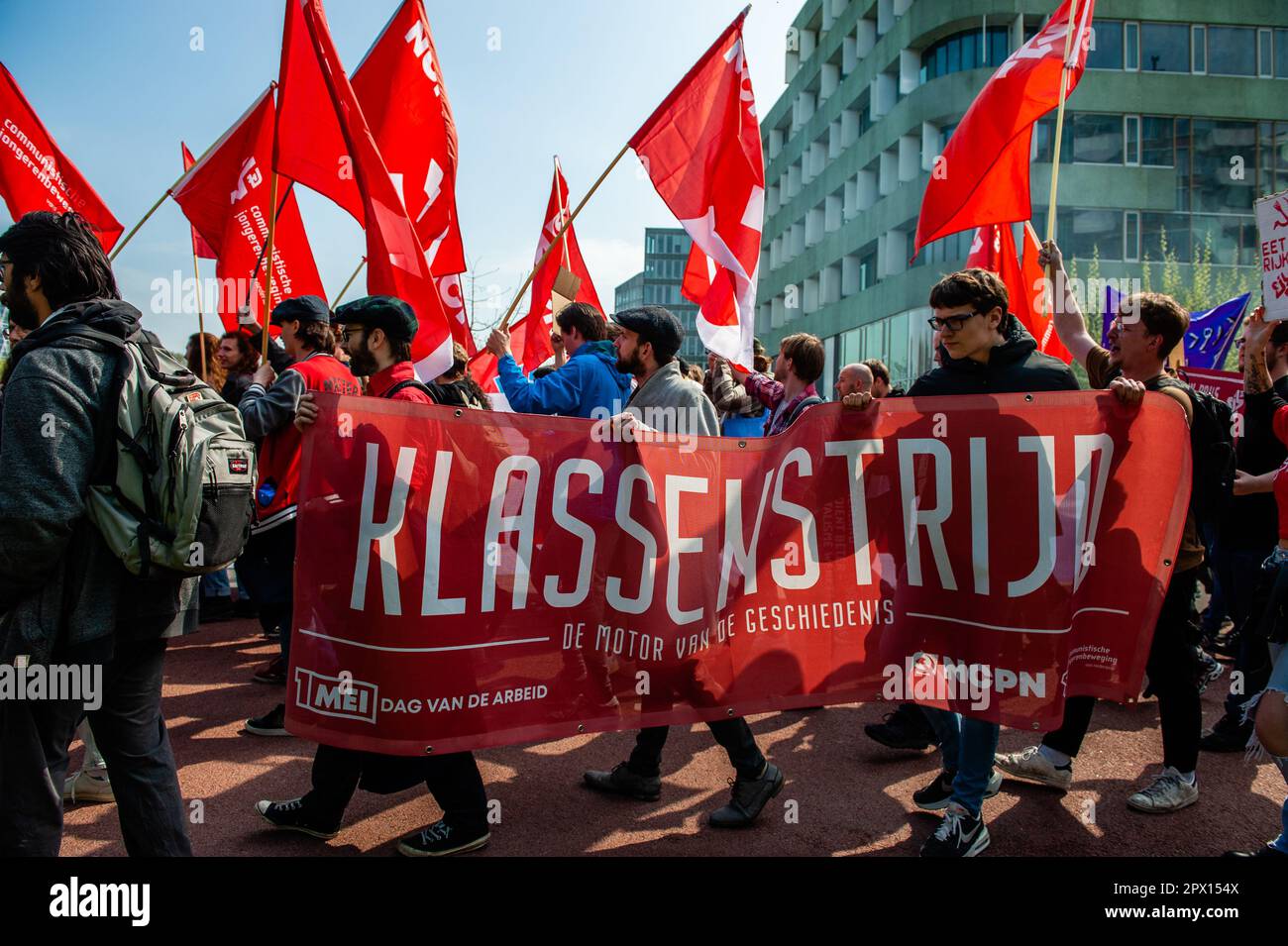 A group of young people is seen walking behind a banner that says ...