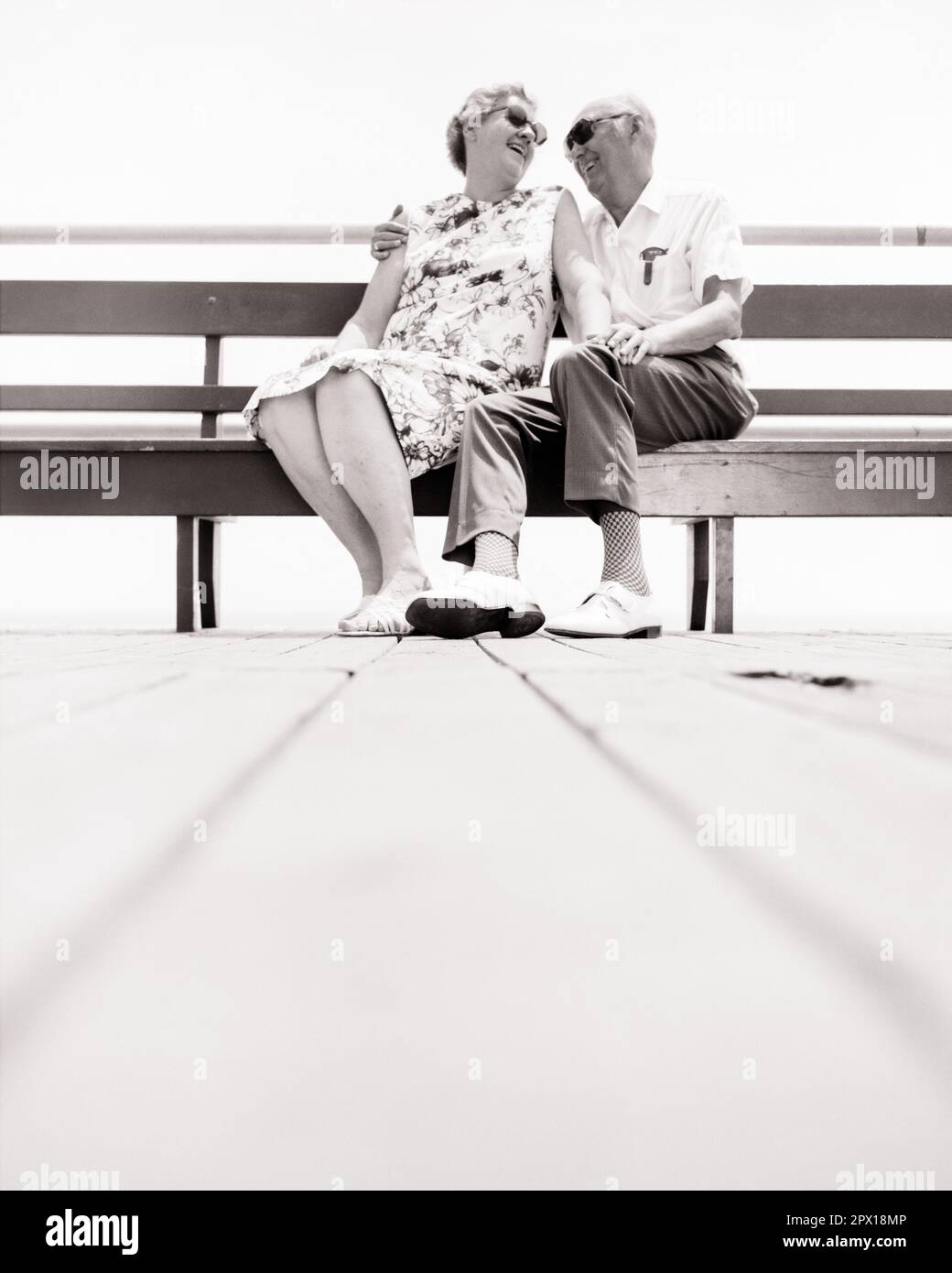 1970s AFFECTIONATE SENIOR COUPLE SITTING ON BOARDWALK BENCH - s19666 ...