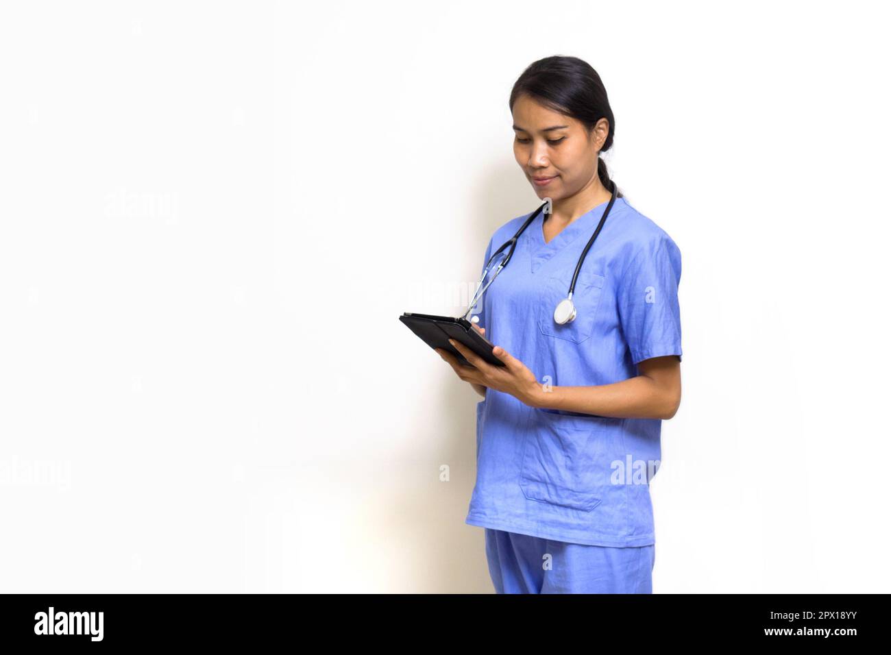 Woman physical therapist in blue uniform and stethoscope typing on ...