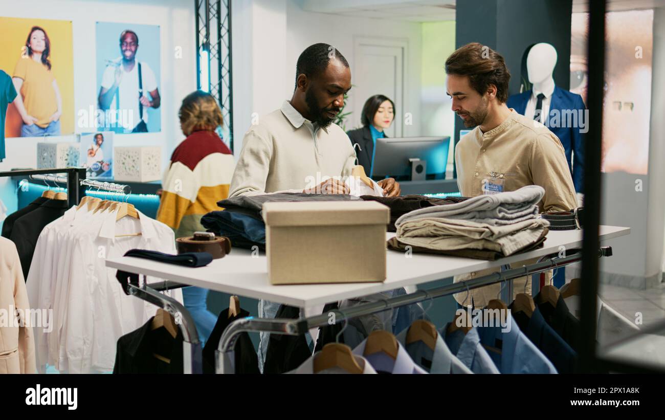 Customer and assistant looking at formal wear in boutique, retail store ...
