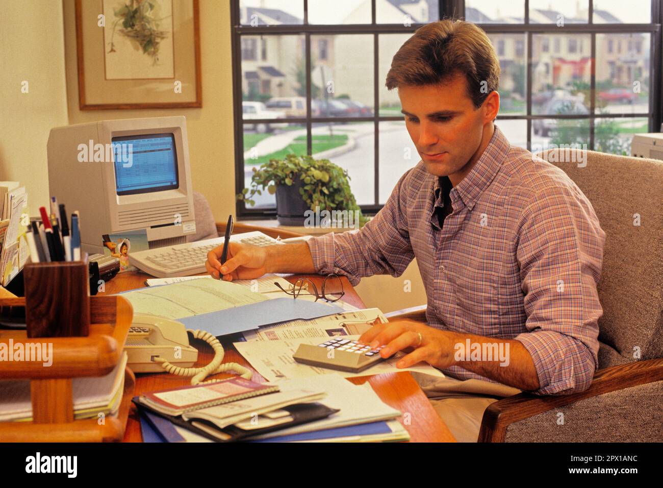 1990s MAN SALESMAN WITH DESKTOP MACINTOSH CLASSIC COMPUTER WORKING OUT ...