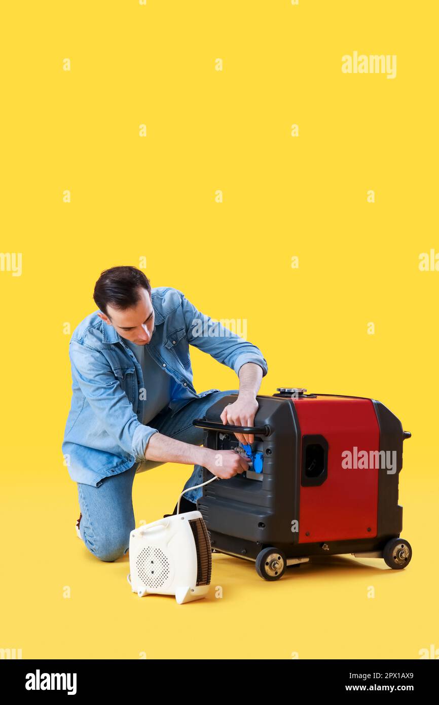 Young man plugging electric fan heater in portable gasoline generator ...
