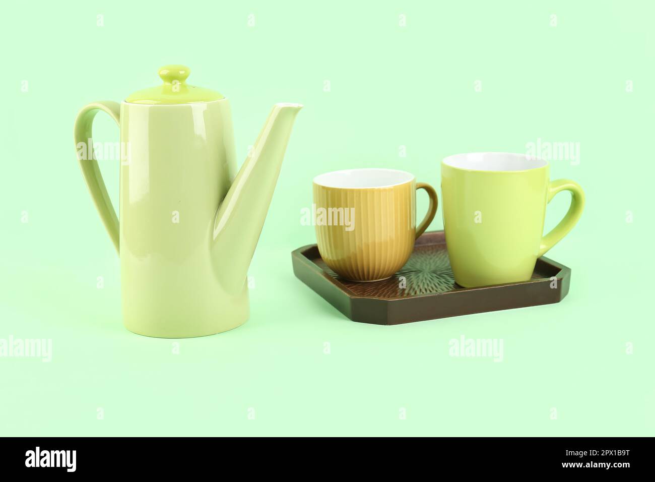 Teapot and tray with mugs on green background Stock Photo - Alamy