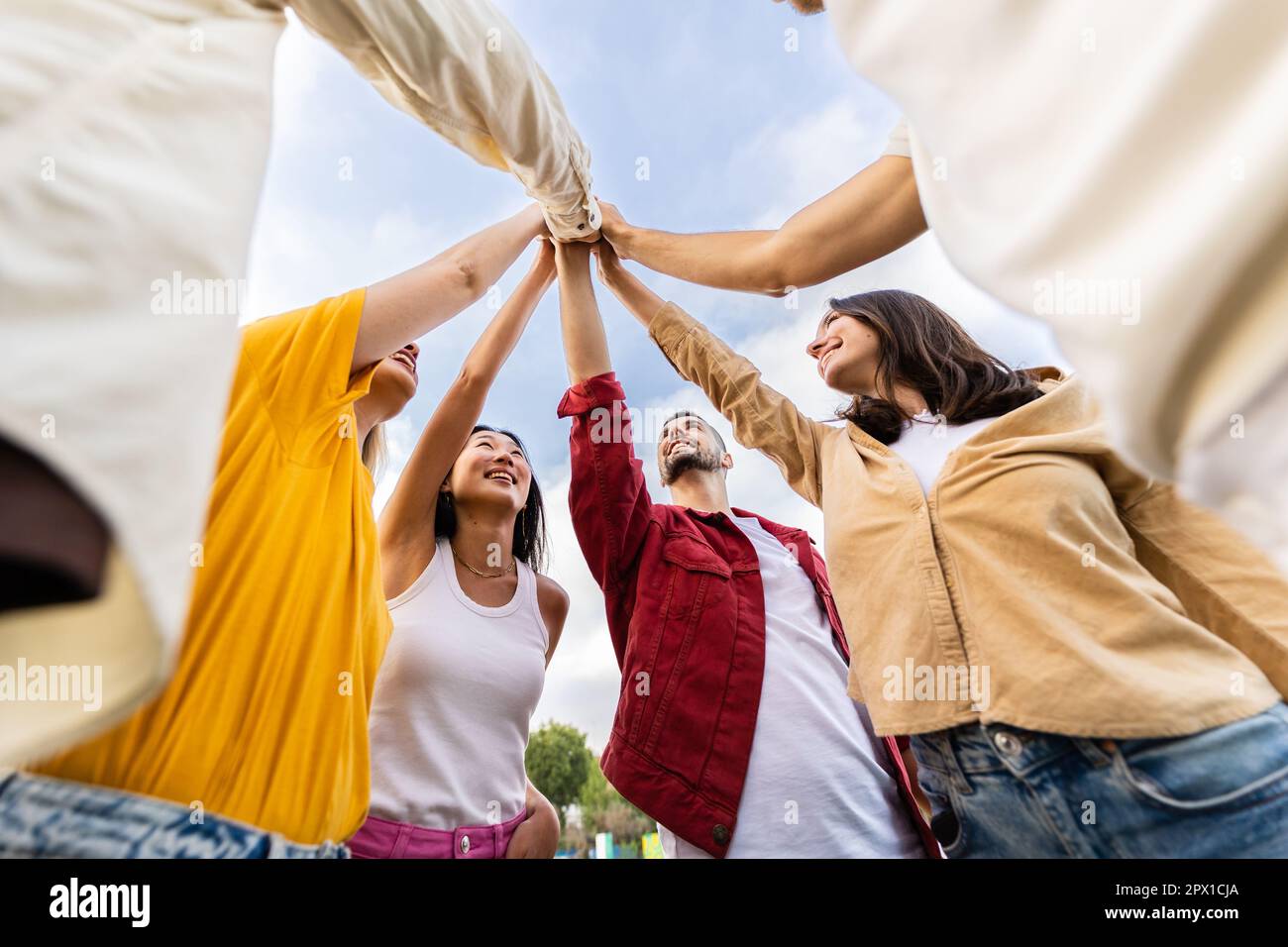 Young group of happy people stacking hands outside Stock Photo - Alamy