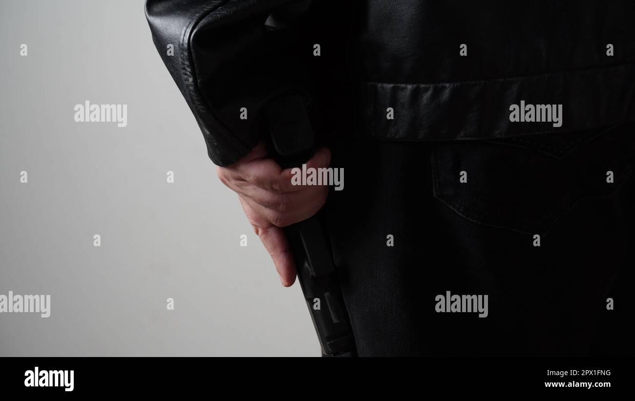 Back view of criminal in black cloths holding gun ready to use it Stock ...