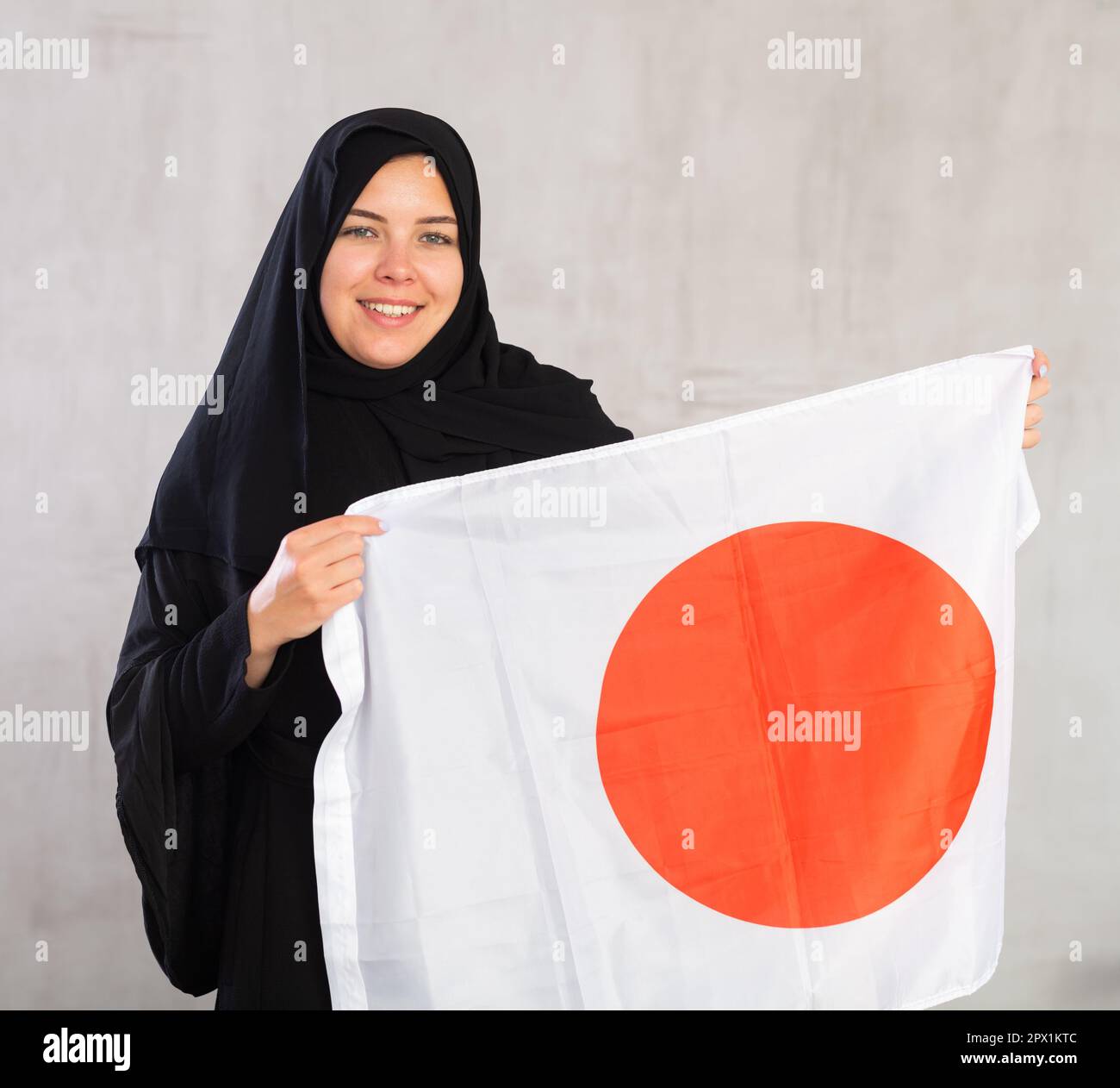 Happy young woman dressed in traditional islamic clothes with japanese ...