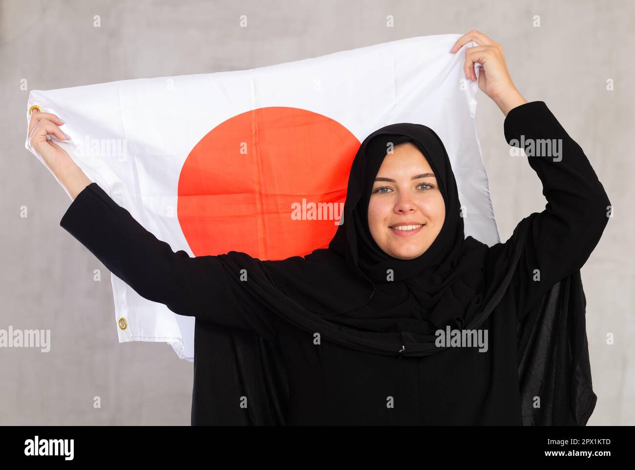Smiling joyful Muslim woman in traditional black hijab holds flag of ...