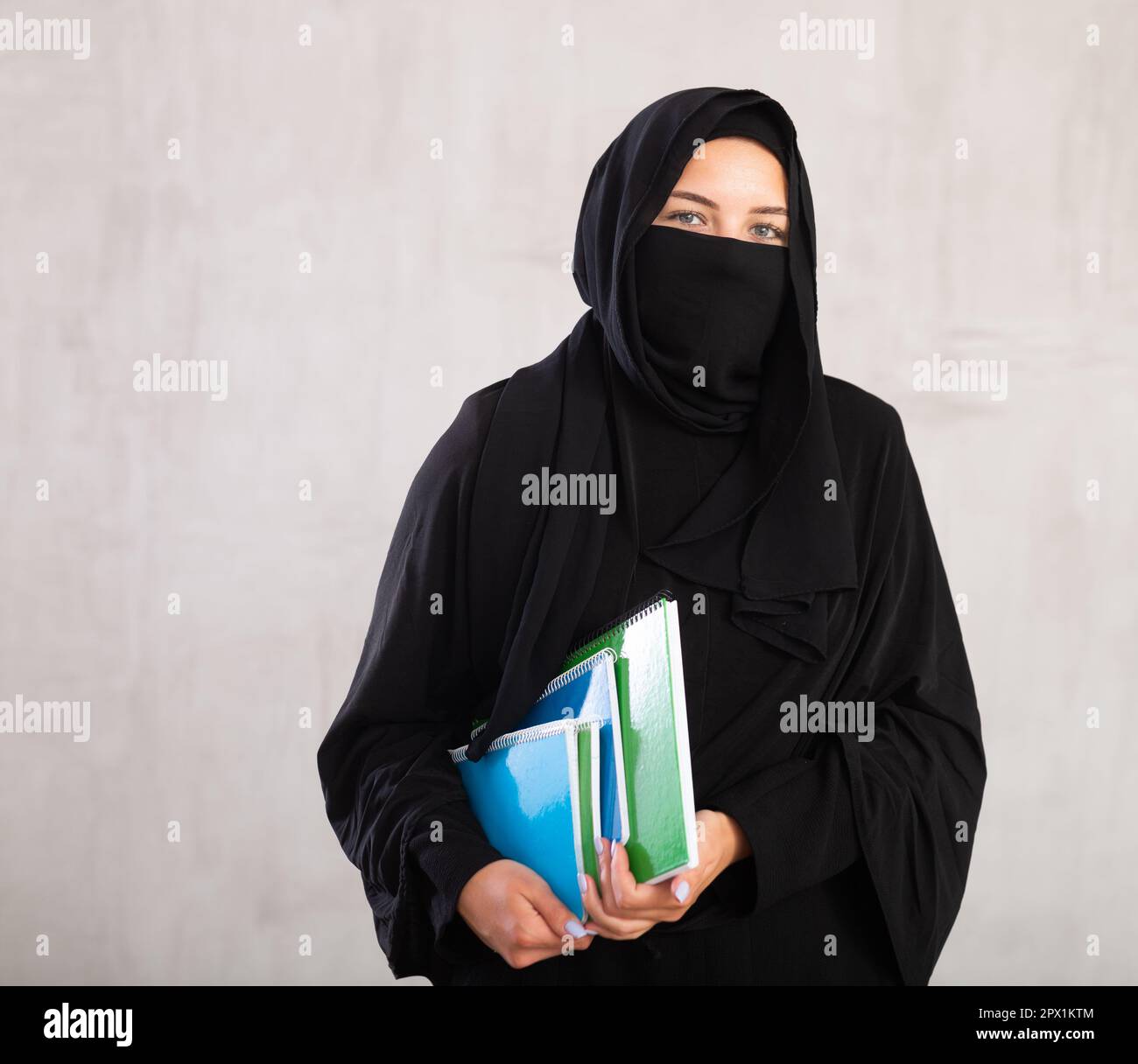 girl with face covered with burka holds lot of thick notebooks. foreign ...