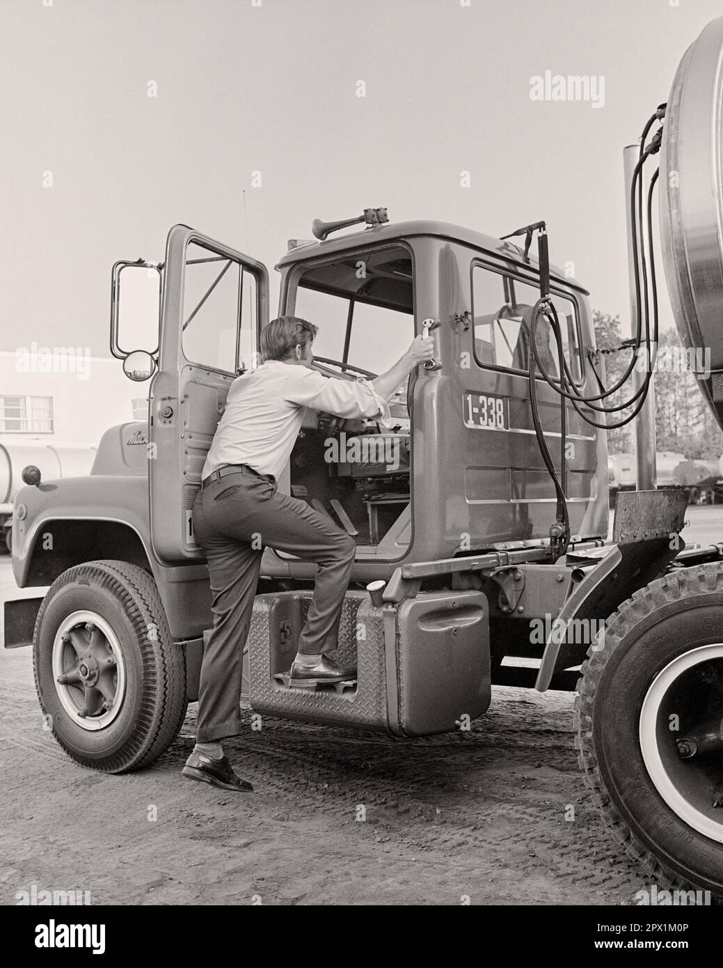 1970s BACK VIEW OF TRUCK DRIVER STEPPING UP INTO THE CAB OF HIS ...
