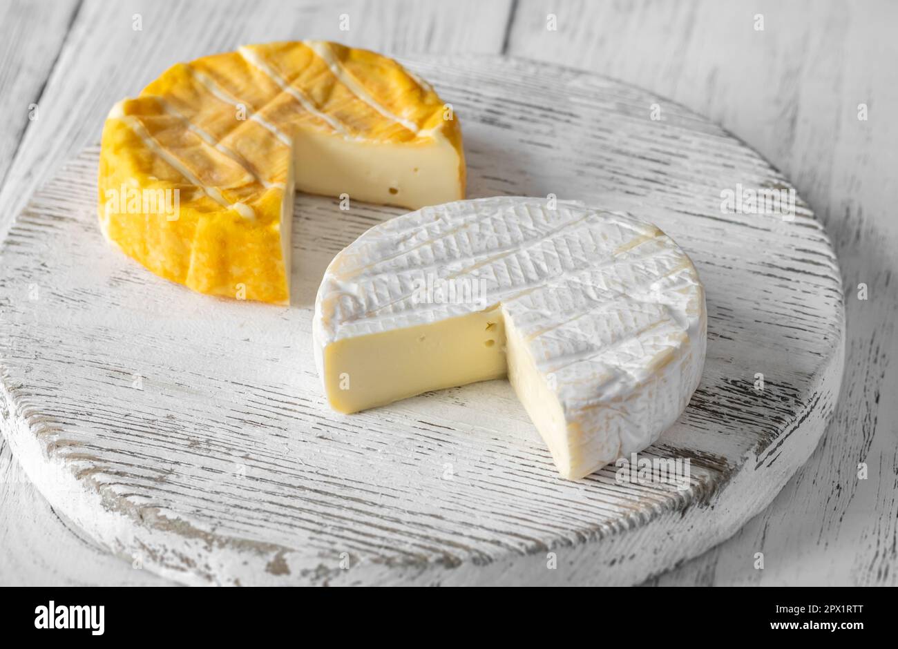 Two camembert cheese wheels on the cutting board Stock Photo - Alamy