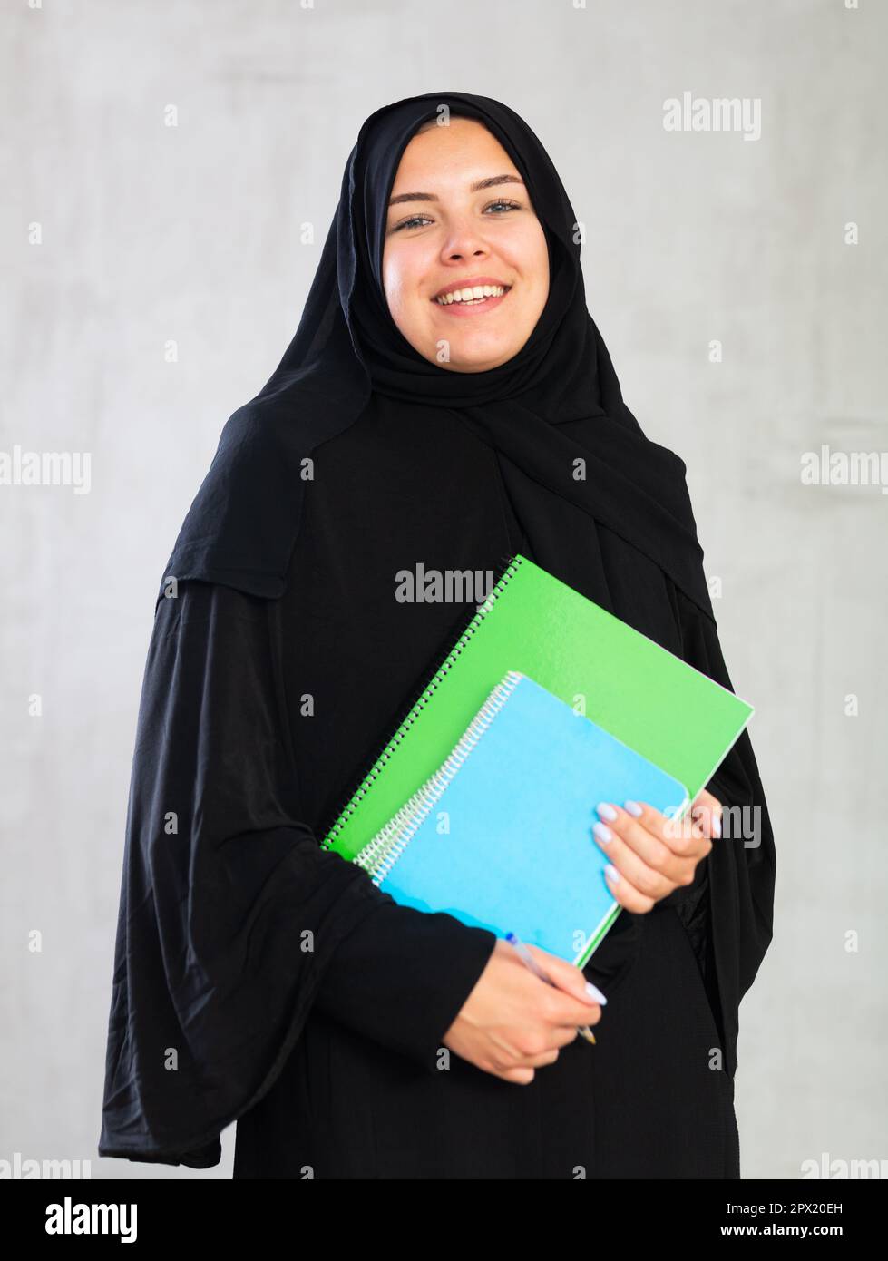 Smiling young female student dressed in traditional islamic clothes ...