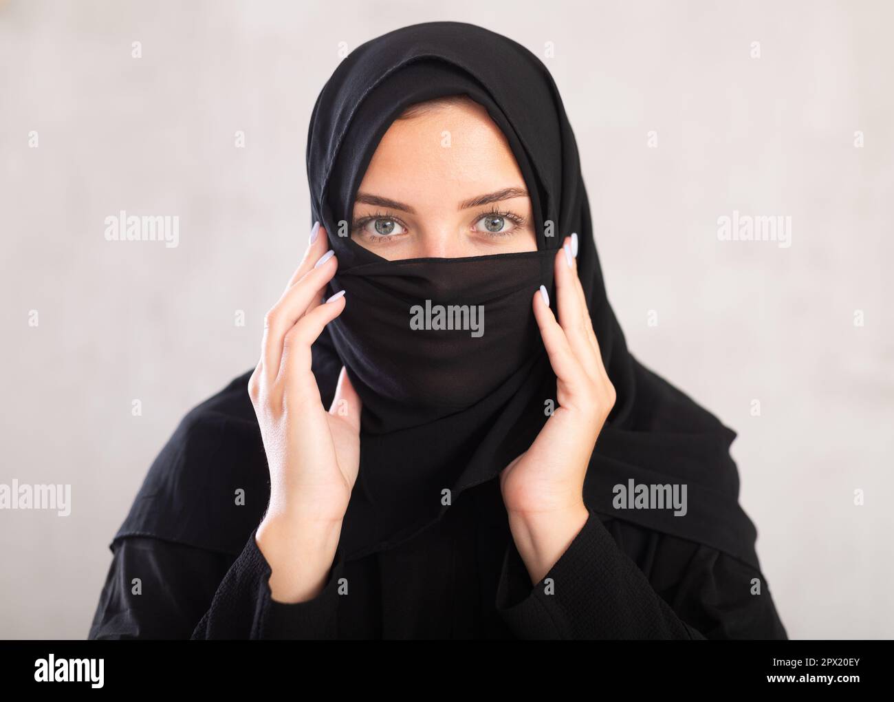 Muslim woman with face covered with burka holds thin fabric of yashmak ...