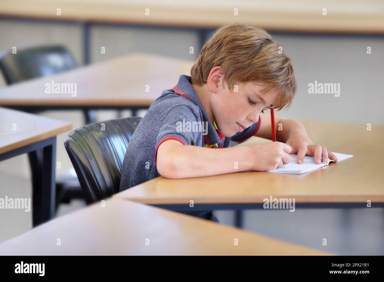 Who ever likes a test. A young boy in a classroom writing a test Stock ...