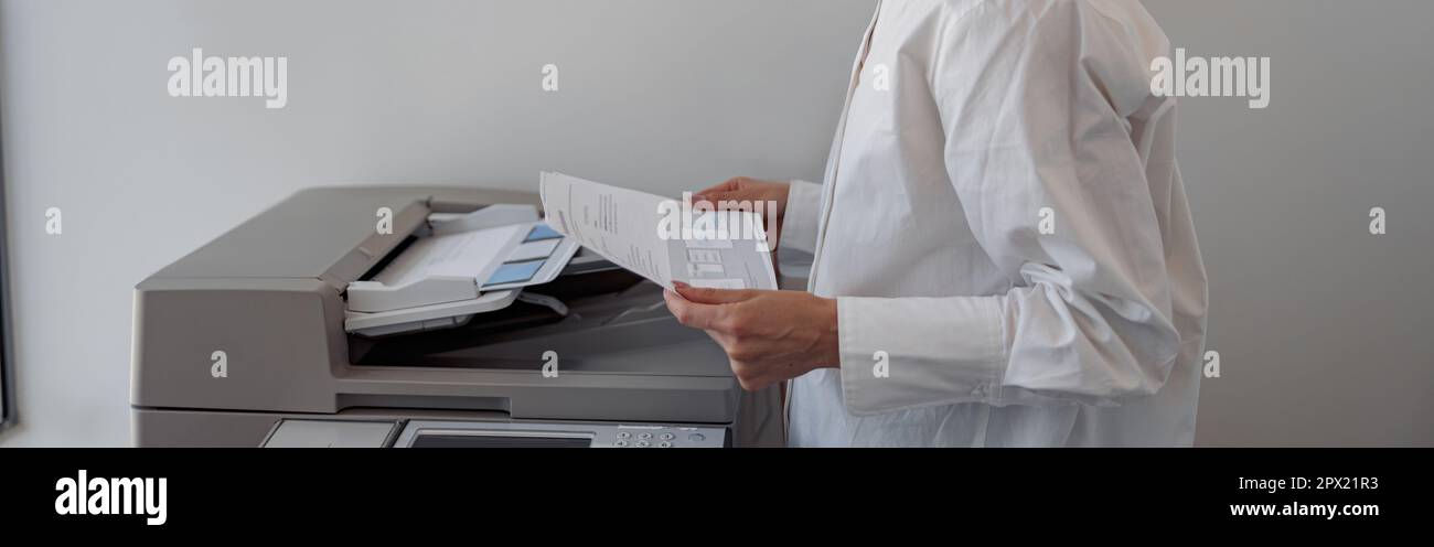 Focused woman worker scanning a document on photocopy machine In modern ...