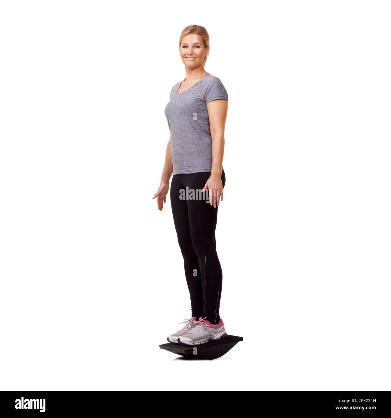 Maintaining her balance. A pretty young woman exercising on a balance ...